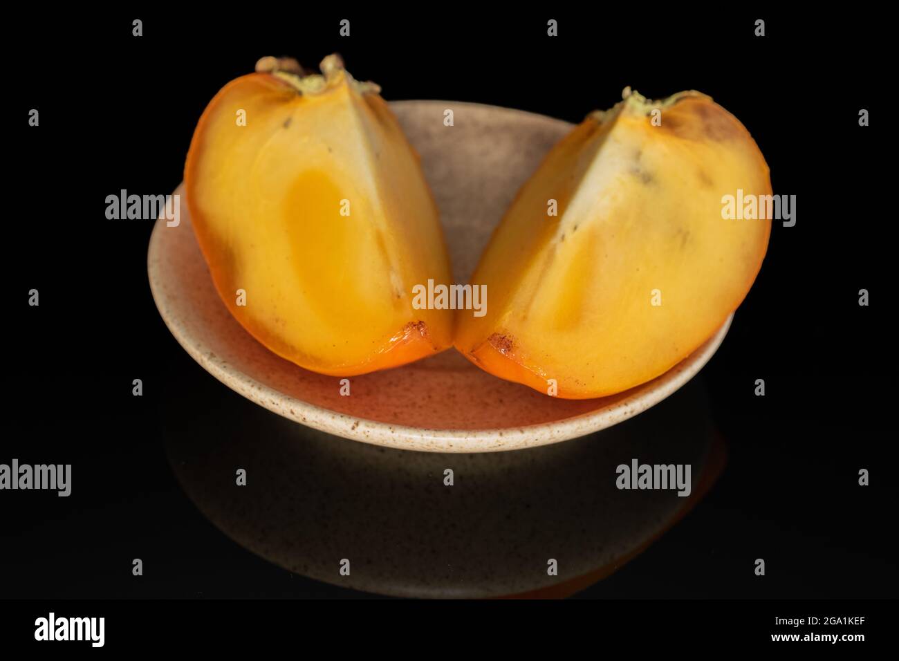 Two slices of juicy organic persimmon, close-up, isolated on black ...