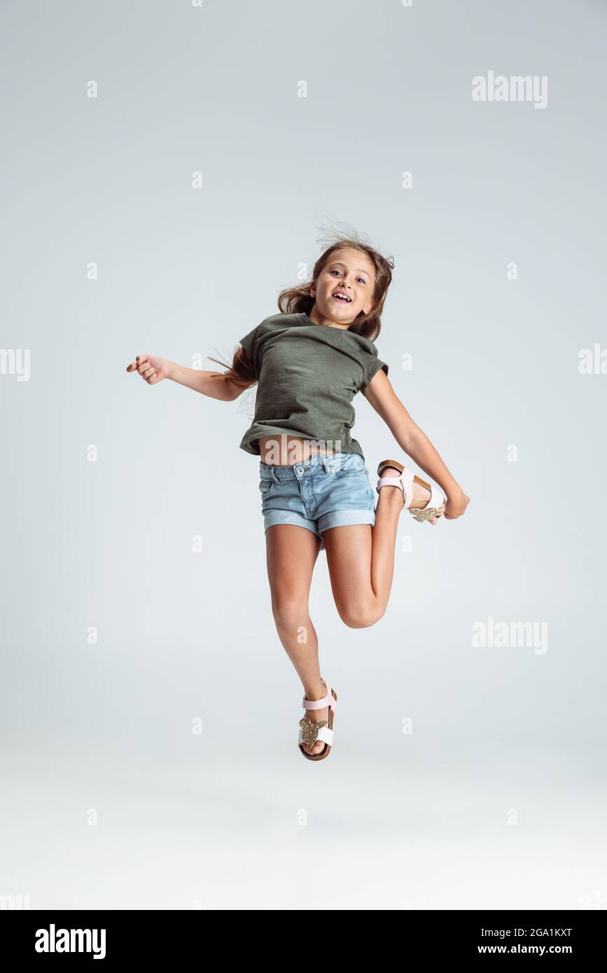Full-length portrait of of beautiful preschool smiling girl jumping ...