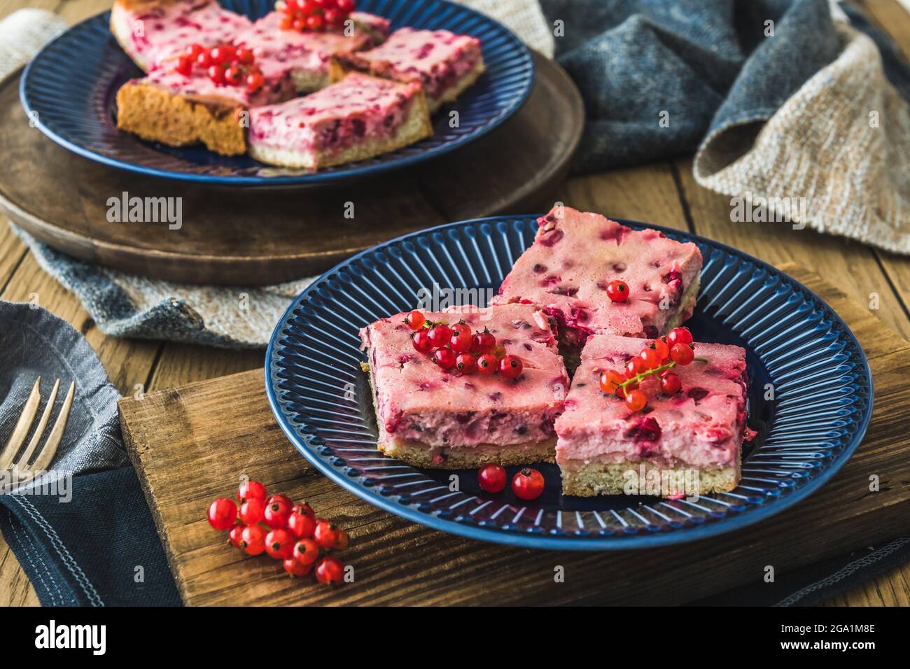 Pieces of creamy red currant pie on a blue plate on wooden background ...