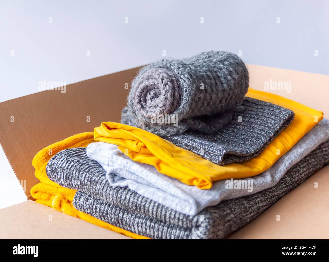 Clothes in cardboard box. Yellow and grey trendy fashion colors. Rolled ...