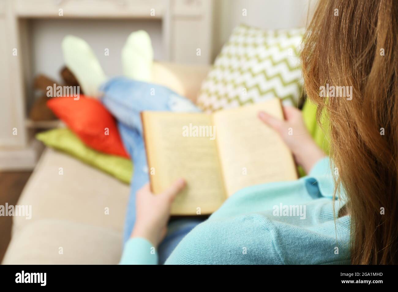 Woman reading book on sofa in room Stock Photo - Alamy