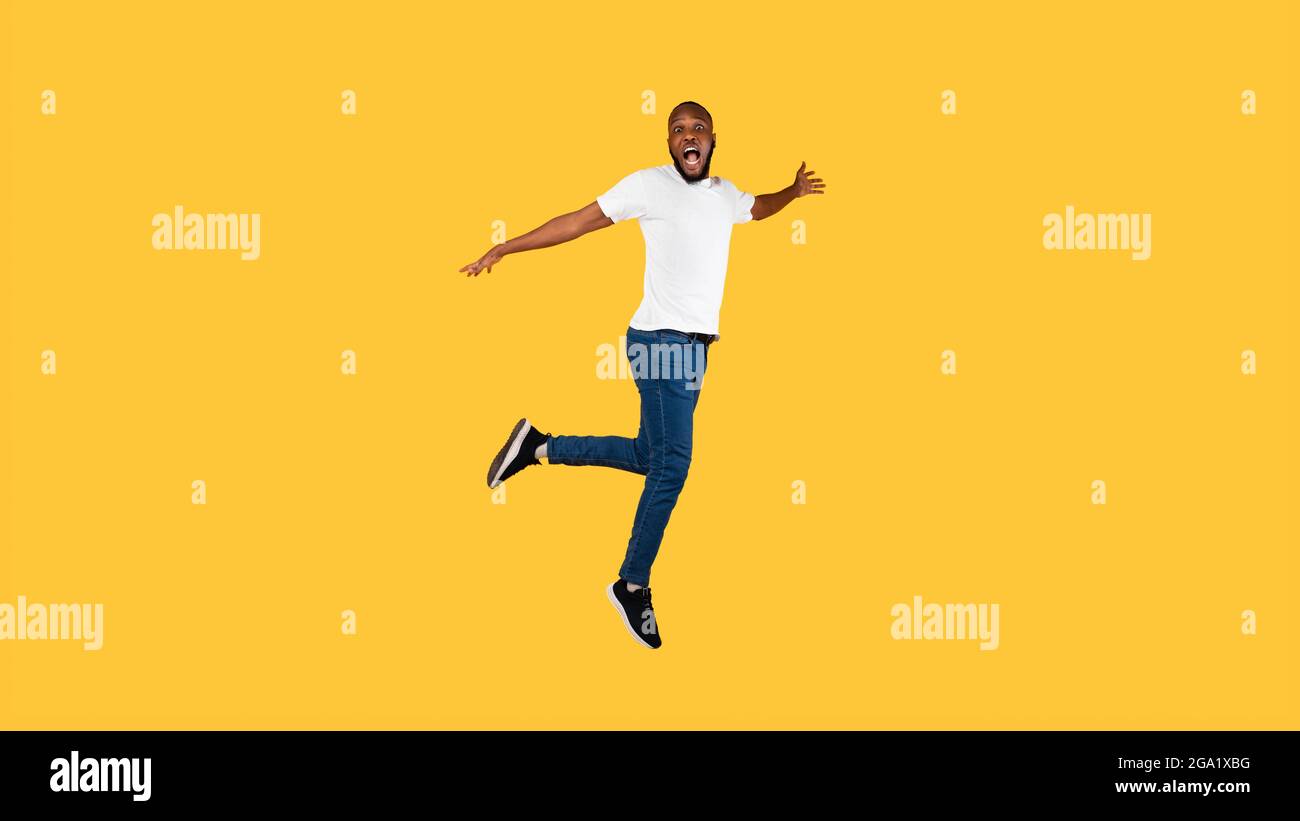 Shocked African American Guy Jumping Looking At Camera, Yellow ...