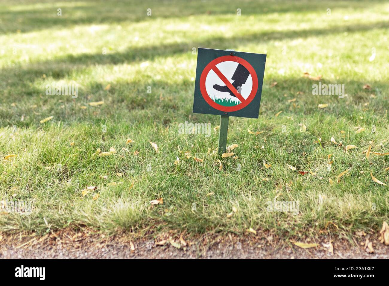 There is a sign on the lawn with a sign forbidding walking on the grass ...