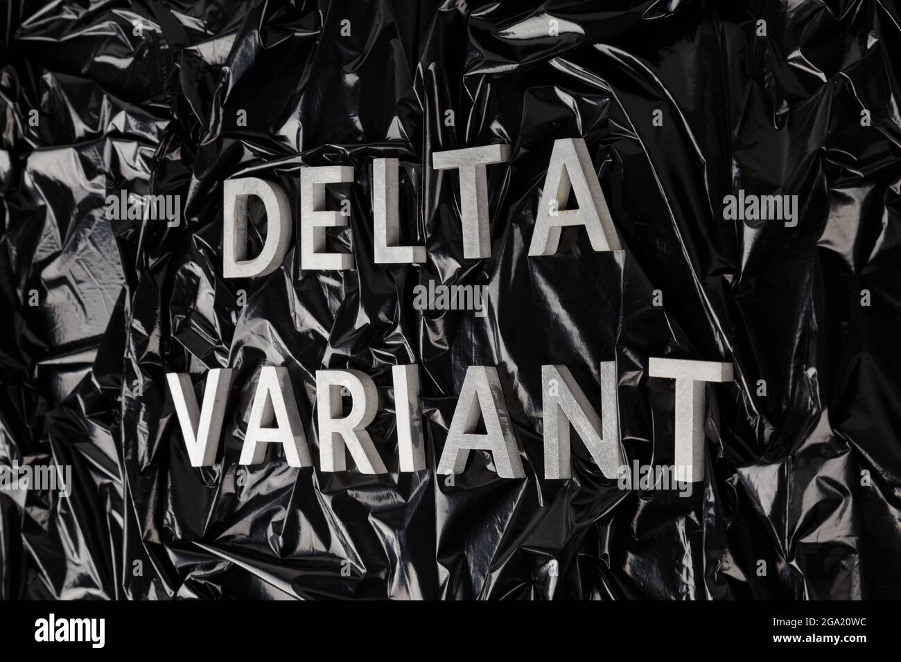words delta variant laid with silver metal letters on crumpled black ...