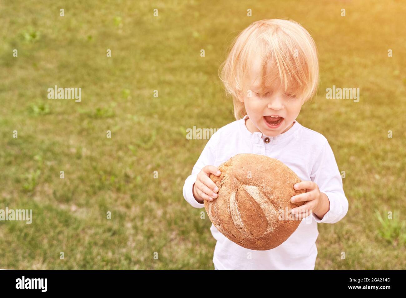 Child holds and bite round bread. Healthy food Stock Photo - Alamy