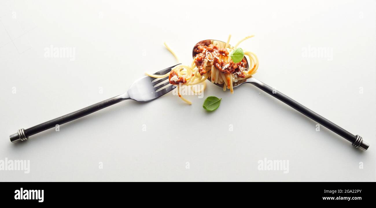 Fork and a spoon with spaghetti bolognese in the light background Stock ...