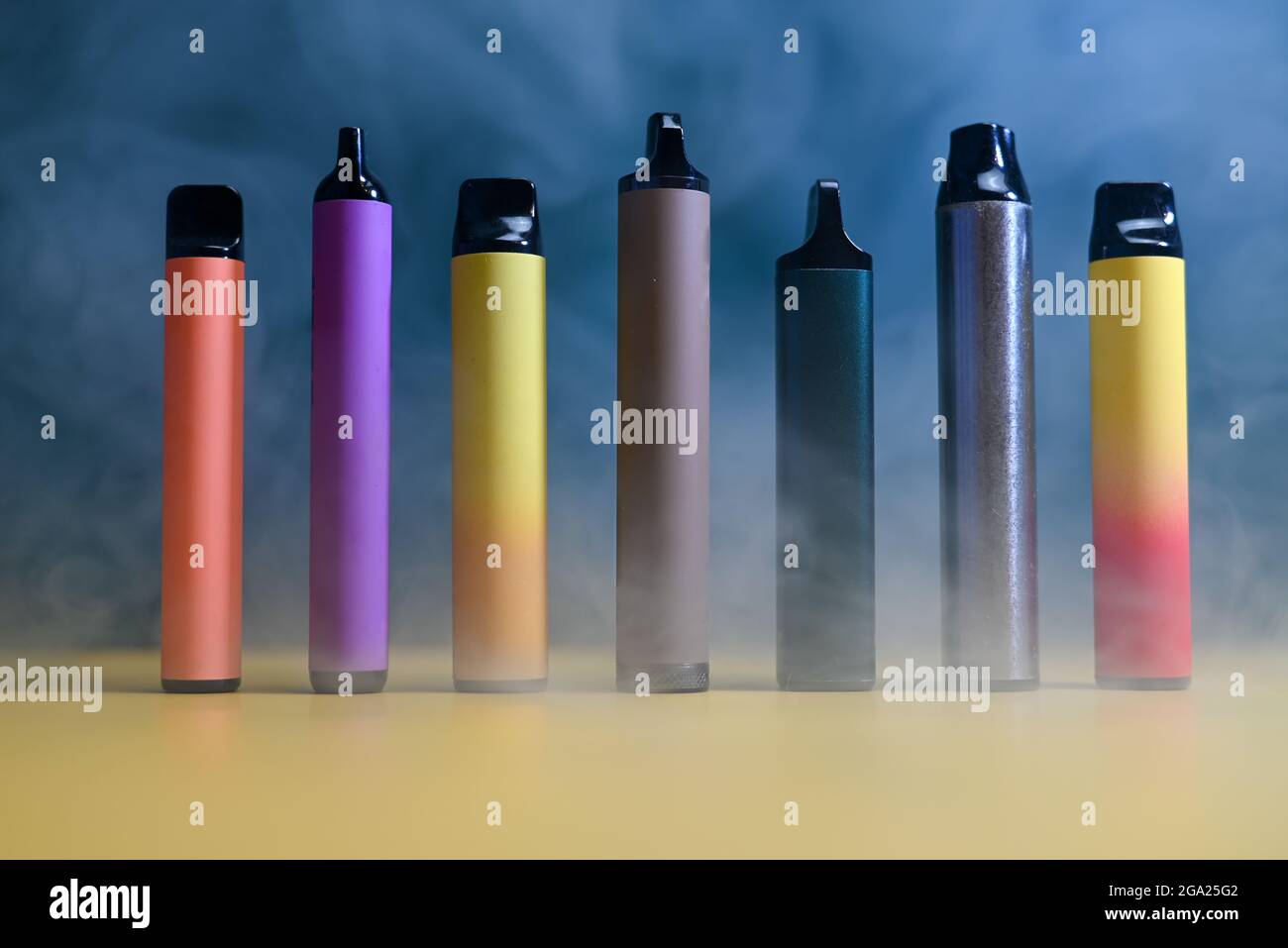 multicolored vape electronic cigarettes on dark green background in ...