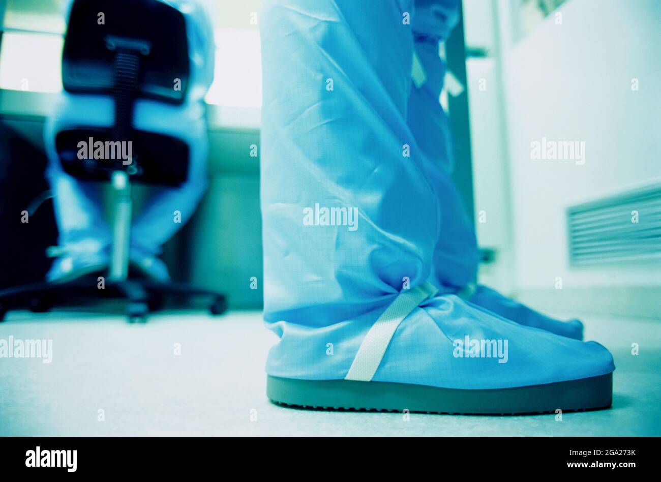 The legs and feet of a researcher standing in a laboratory doing work ...
