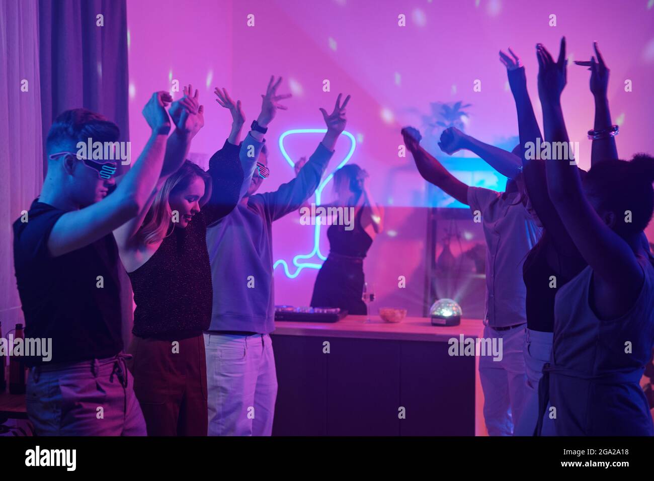 Young intercultural friends in smart casualwear raising arms while ...