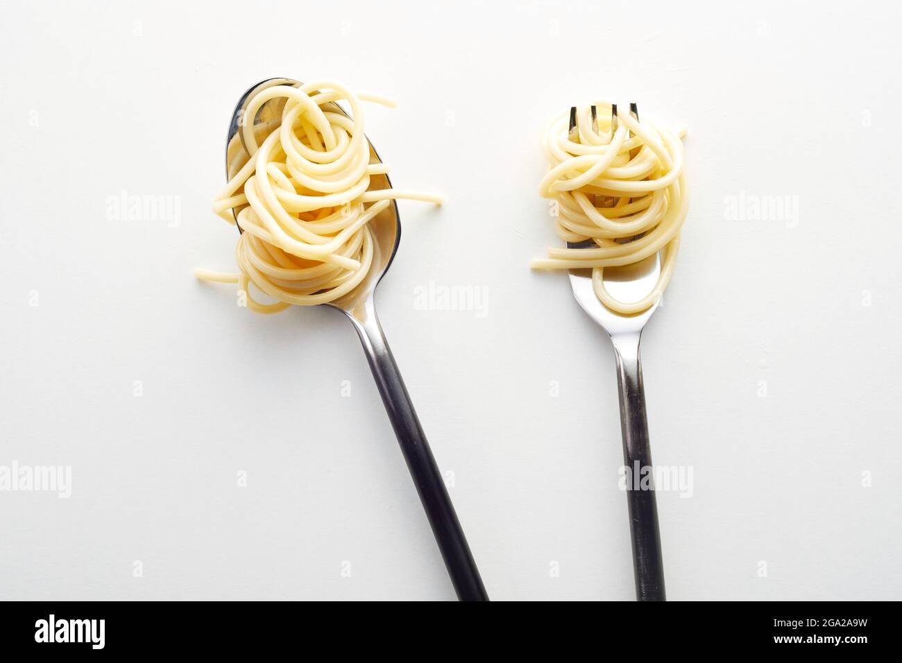 Top view of a fork and spoon with spaghetti in the white background ...