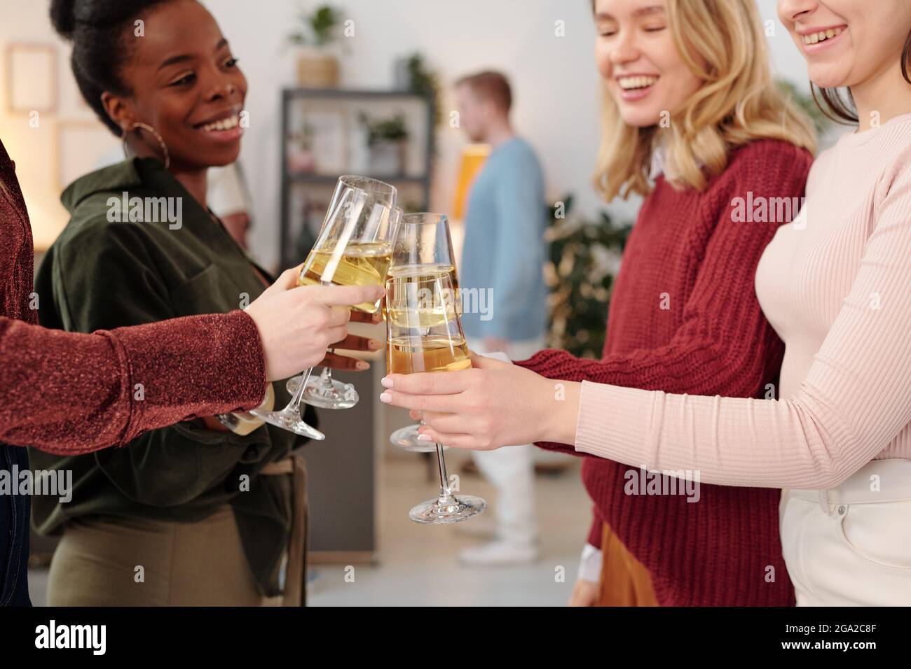 Happy young intercultural women in smart casualwear clinking with ...