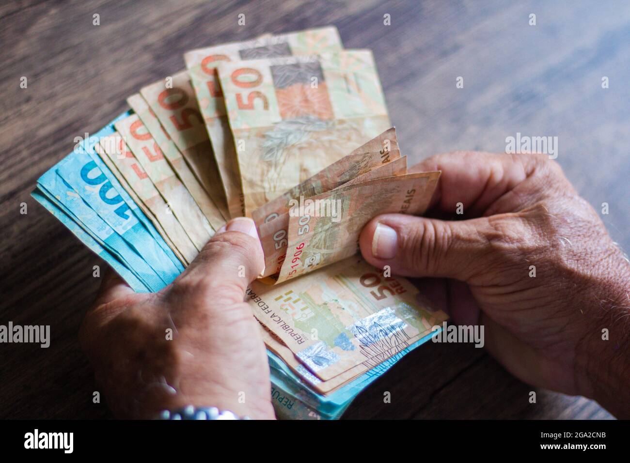 Man holding real Brazilian money banknotes Stock Photo - Alamy