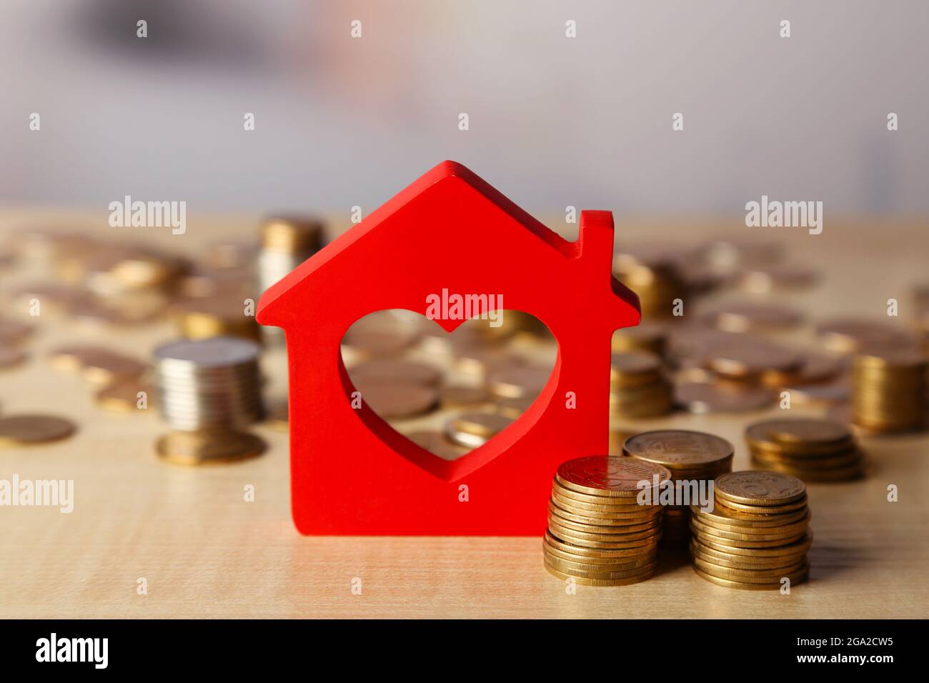 Model of house with coins on bright background Stock Photo - Alamy