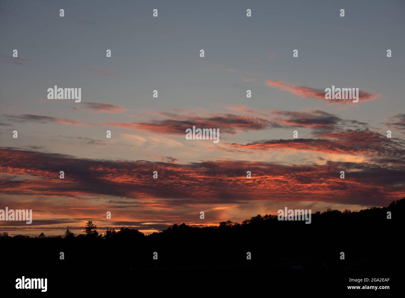 Red clouds lit up by the sun at sunset Stock Photo - Alamy