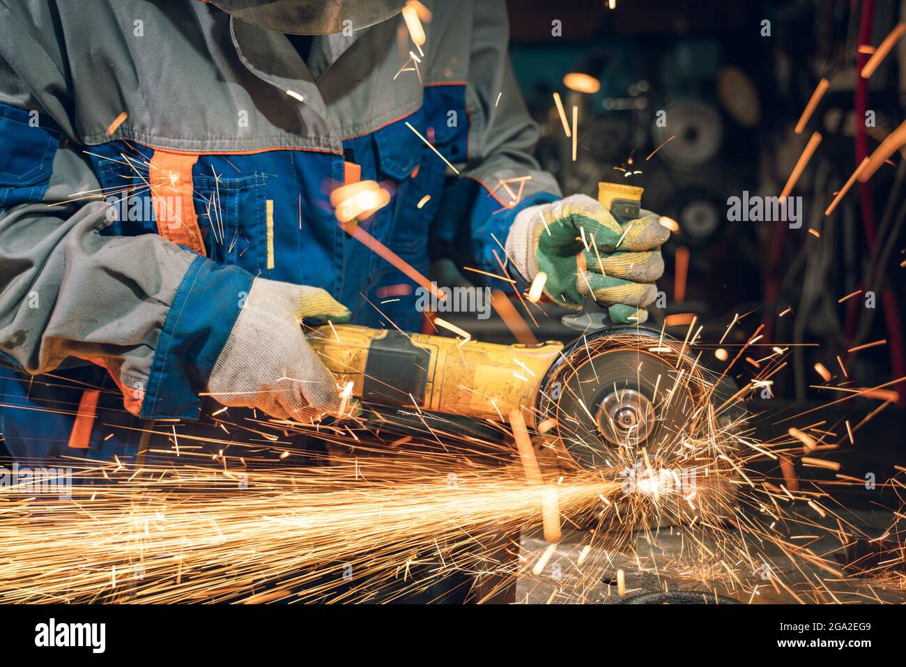 Locksmith in special clothes and goggles works in production. Metal ...