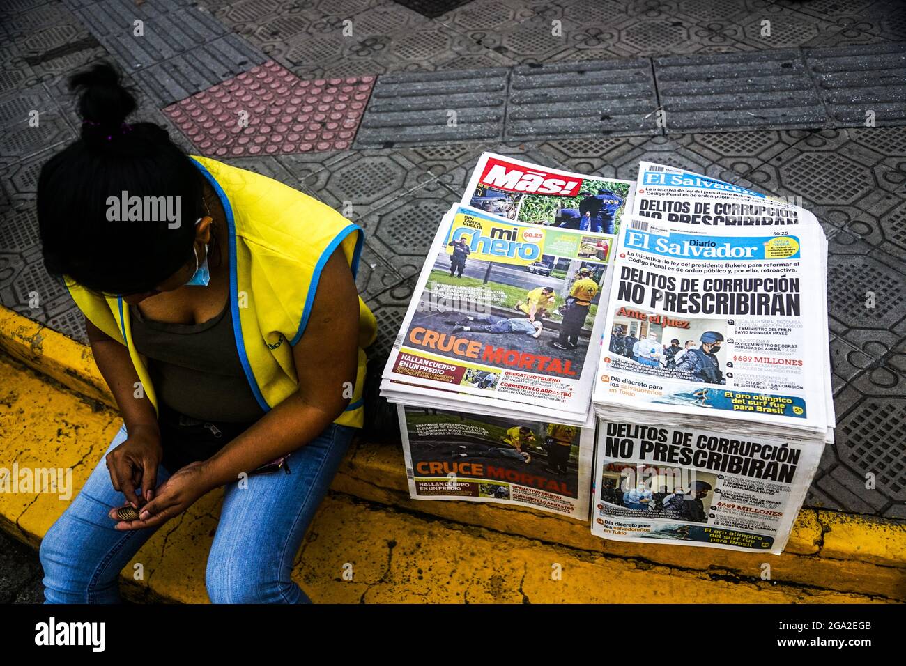 A woman selling newspapers rests as she awaits for customers Stock ...