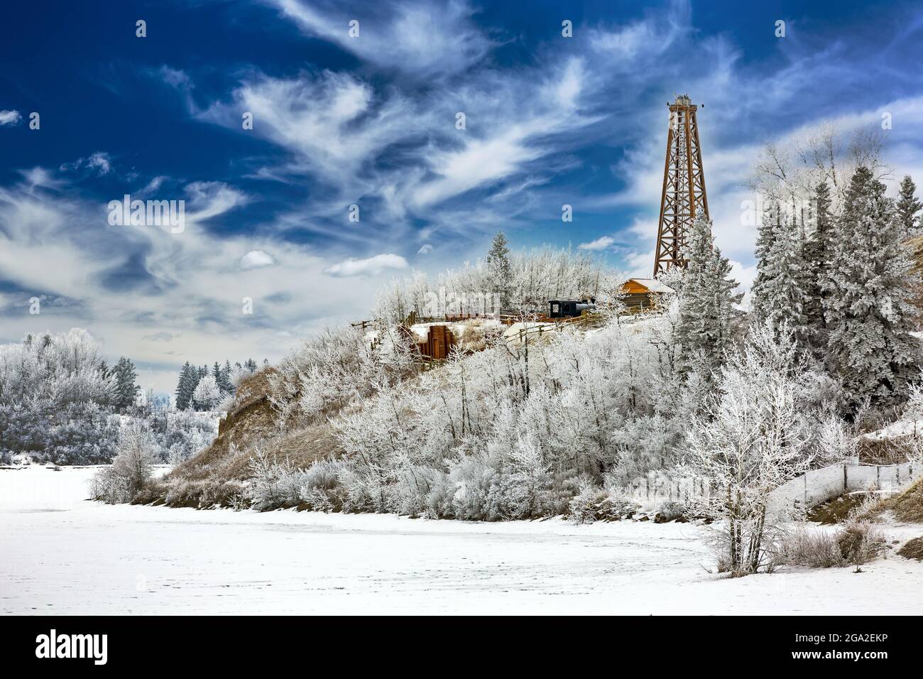 Old wooden oil rig on a hill along a shoreline with heavily frosted ...