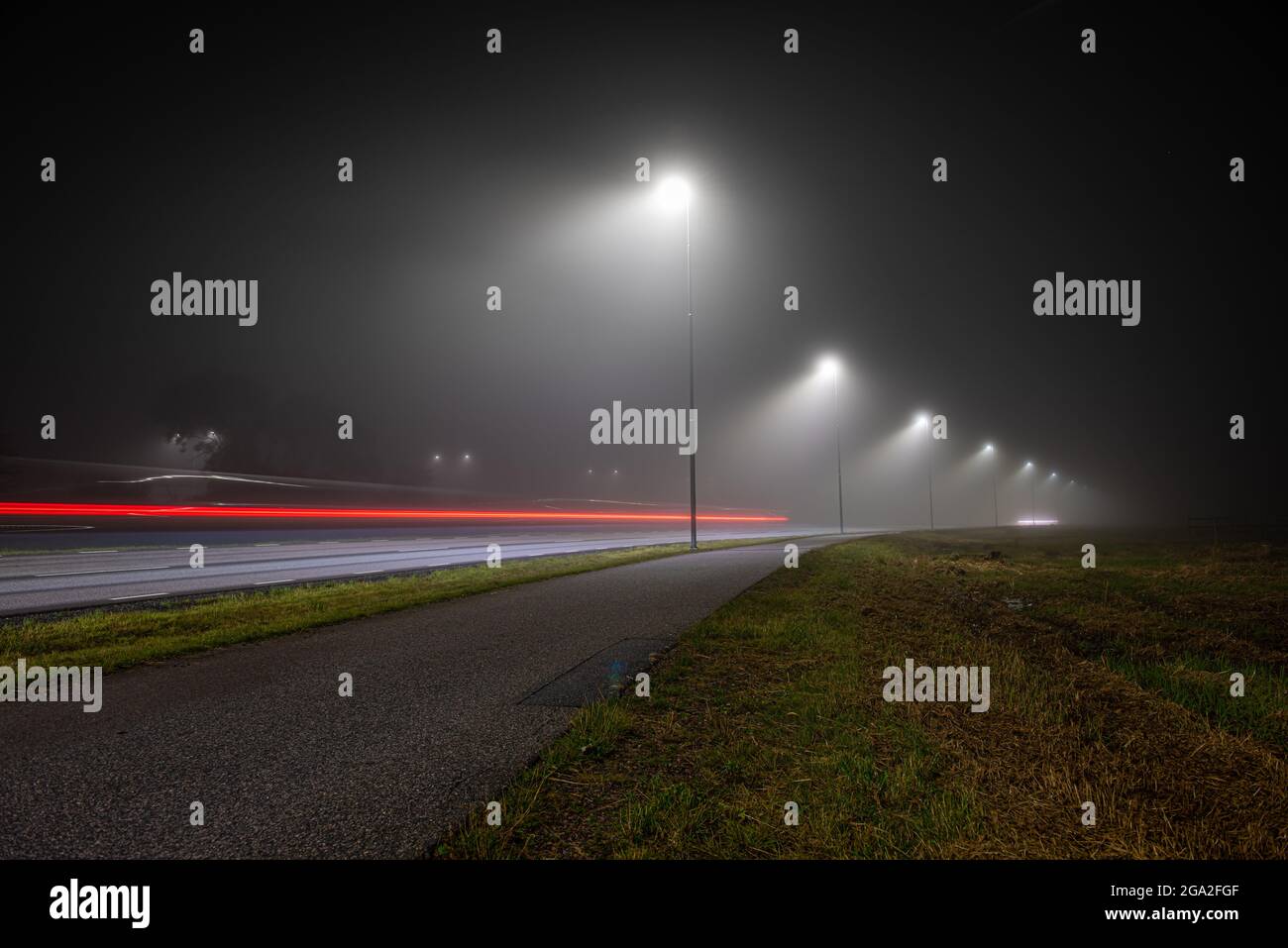 Long exposure of car lights on a lonely road at night in dense fog ...