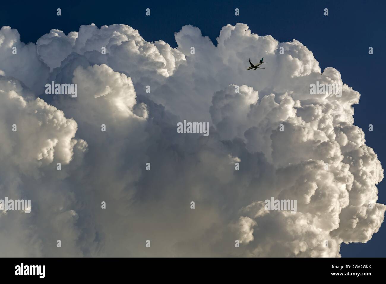 Large puffy white storm clouds and blue sky with airline jet flying ...