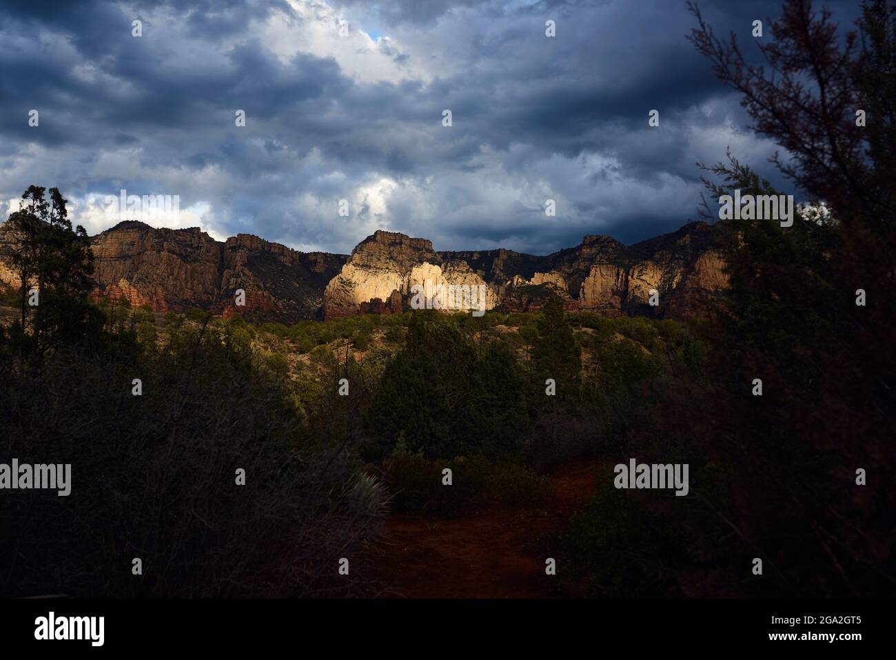 Gathering storm clouds and dramatic light on red rock mountains with ...