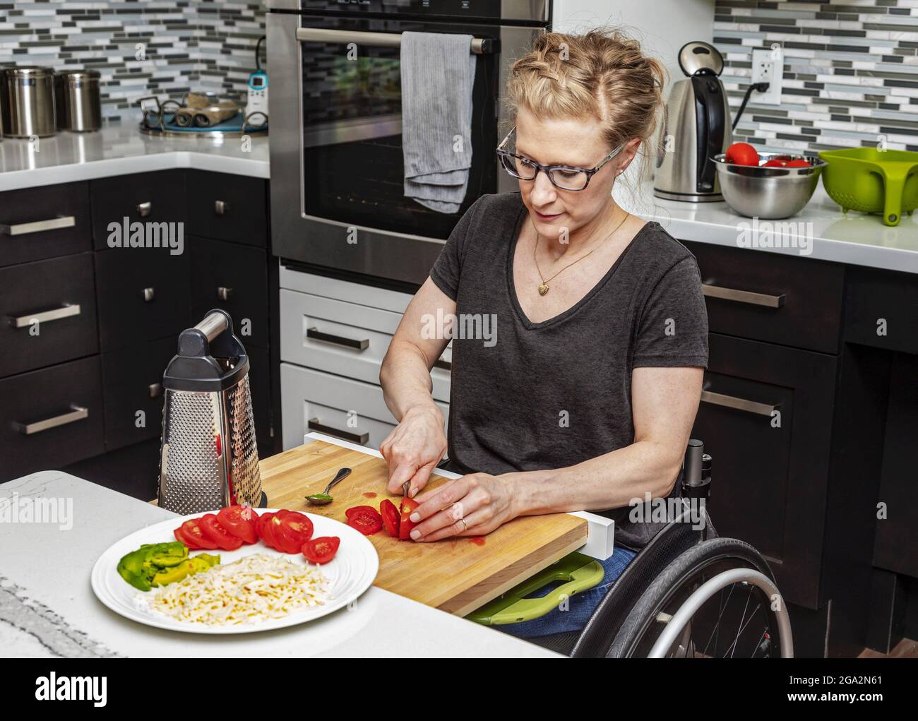 A paraplegic woman preparing a meal for her family in her kitchen while ...
