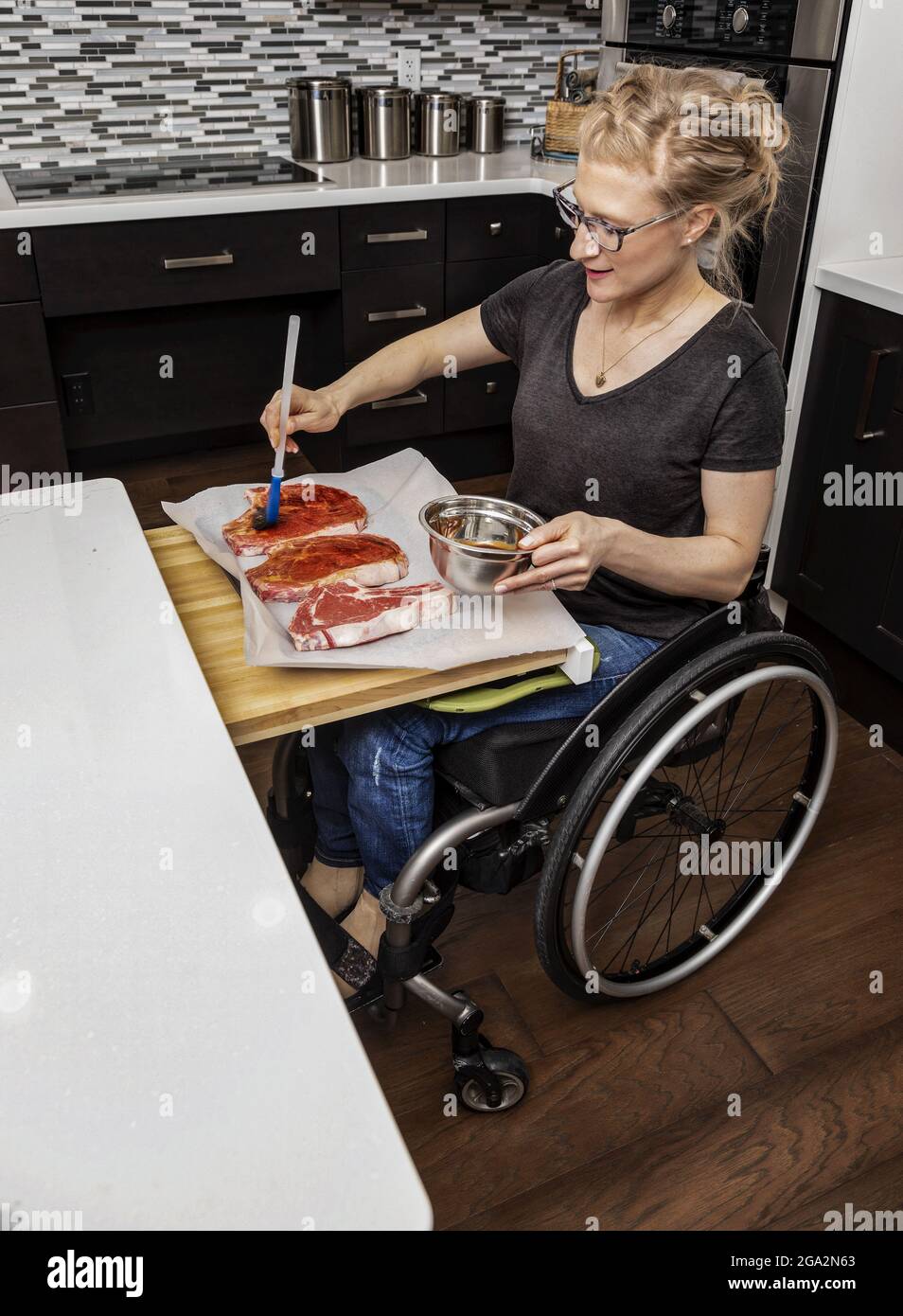 A paraplegic woman preparing steaks for a meal for her family in her ...