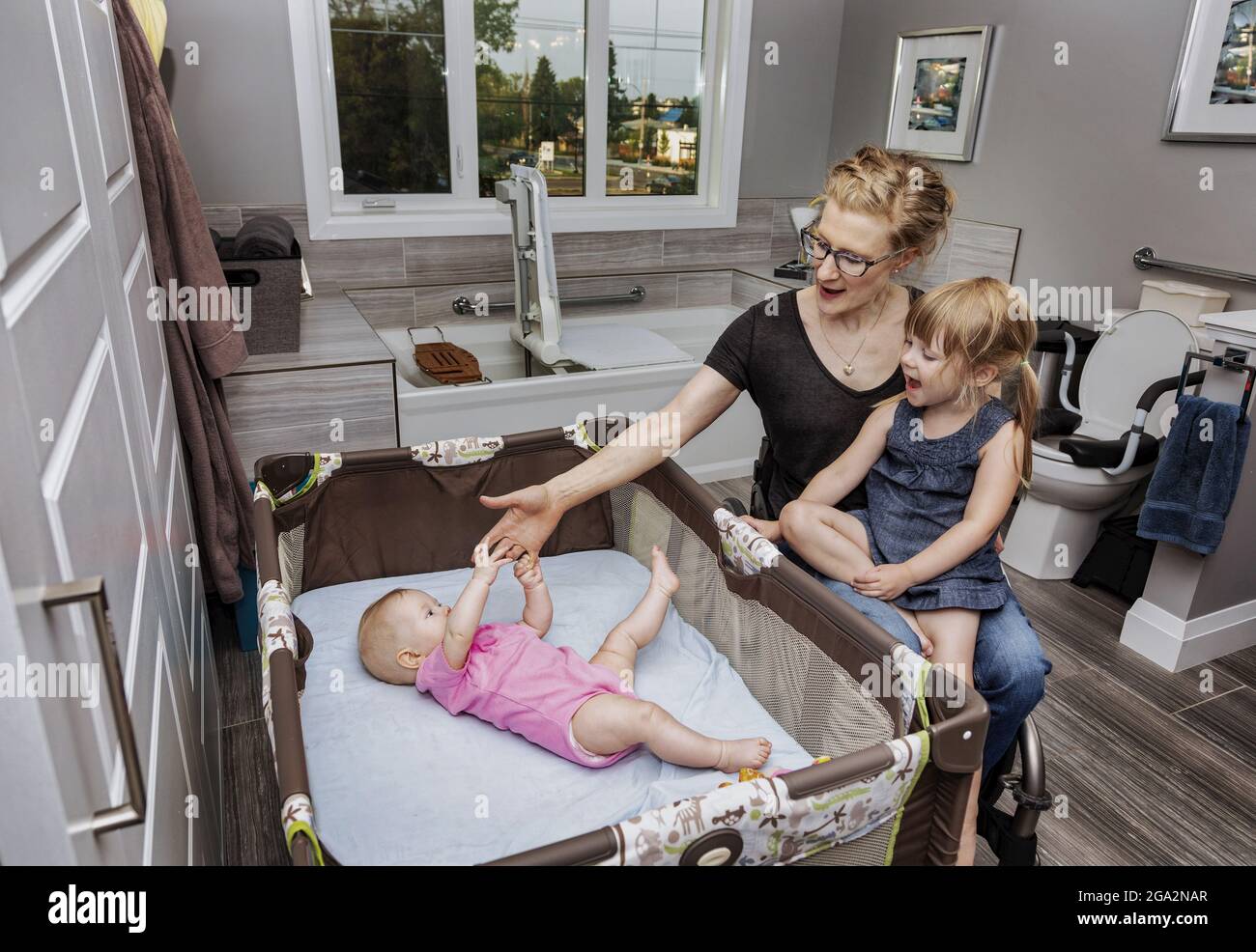 A paraplegic mother playing with her baby in a play pen and holding her ...