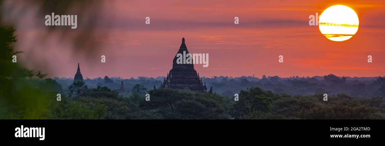 Silhouettes of pagodas with the sun rising above the Plain of Bagan at ...