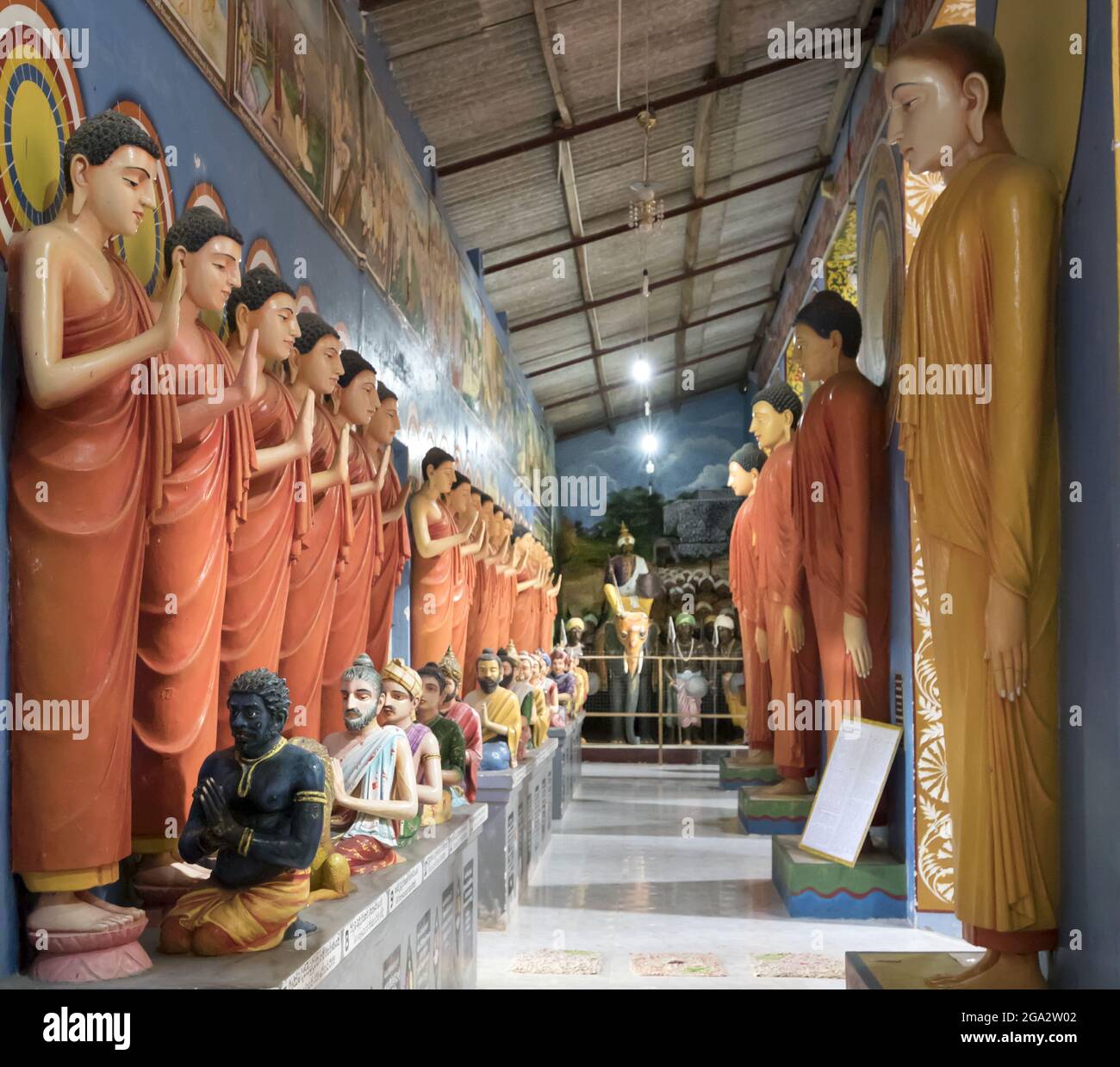 Hallway lined with statues of Standing Buddhas and sculptures of holy ...