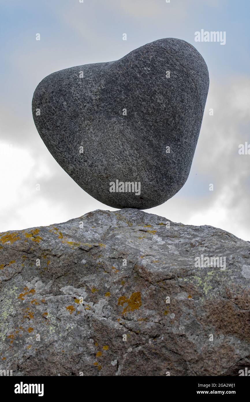 A heart-shaped boulder balanced on a rock surface on Uttakleiv Beach in ...