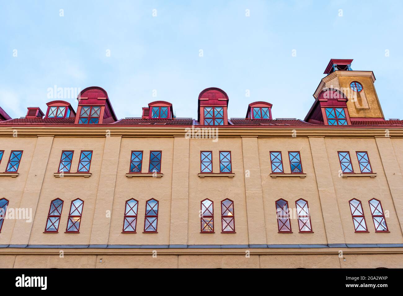 Beige brick building with windows, red roof and blue sky Stock Photo ...