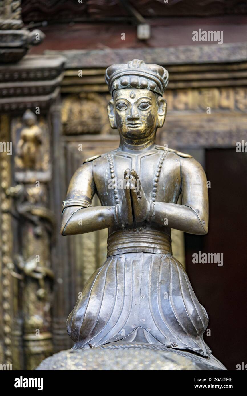 Close-up of a brass statue of a praying figure in Kwa Bahal Golden ...