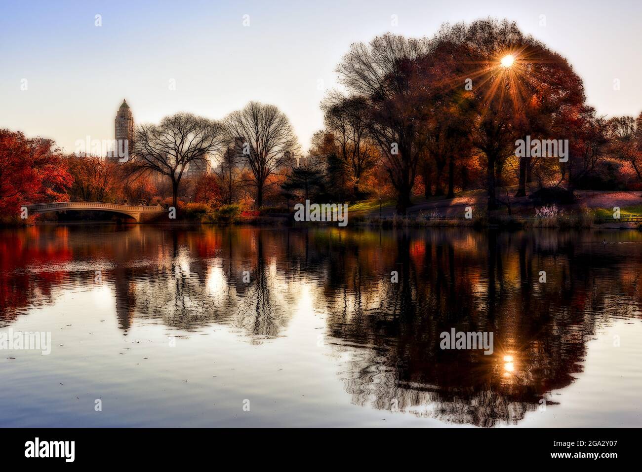 Sun rising above autumn coloured foliage on The Lake, Central Park; New ...