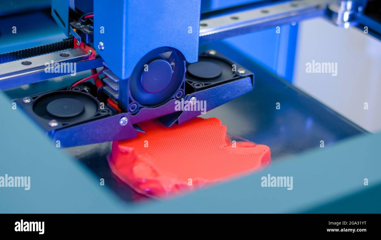 Three dimensional printing machine prints physical red 3D model - close ...