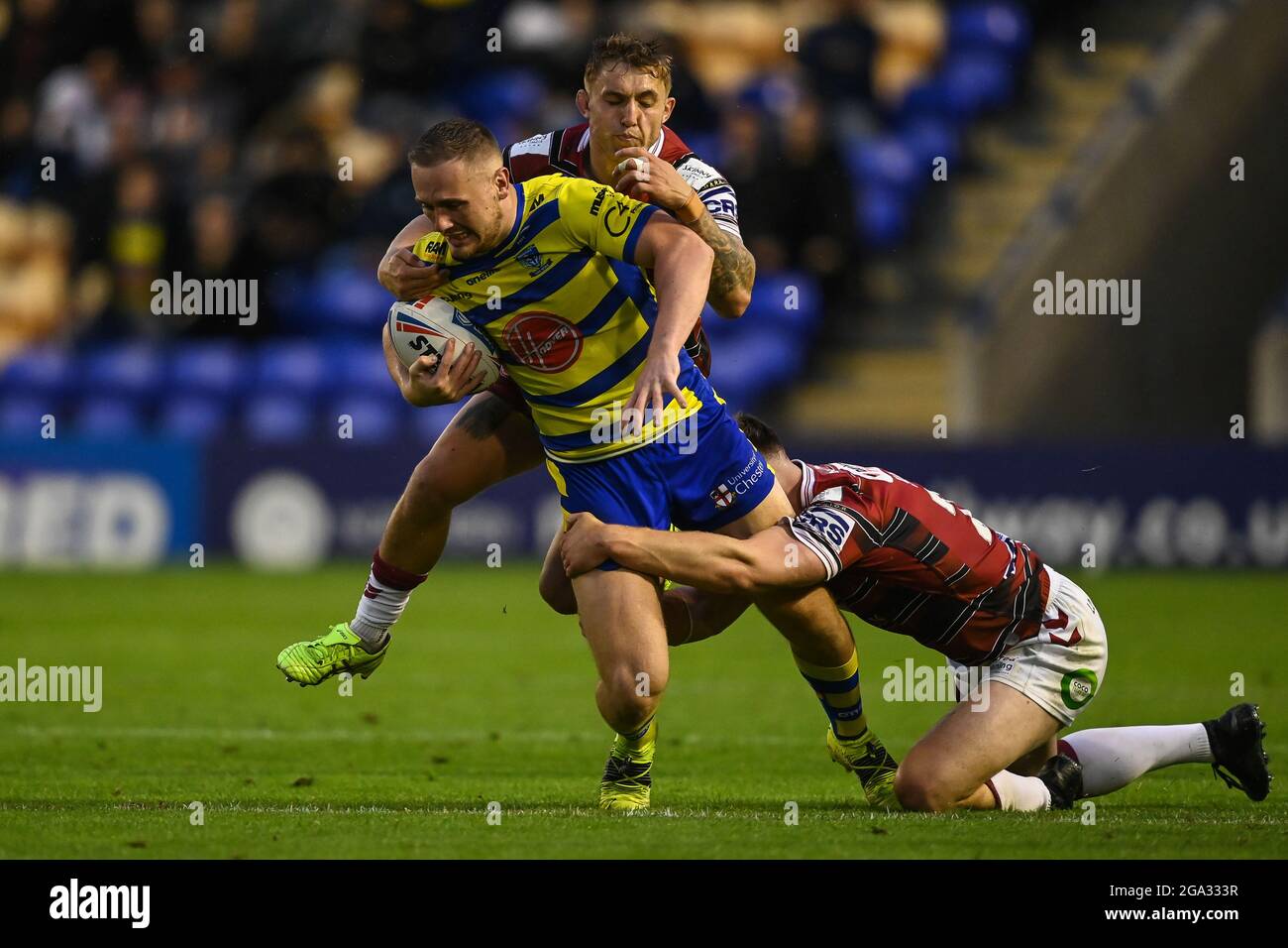 Ben Currie (11) of Warrington Wolves is tackled by Sam Powell (9) and ...