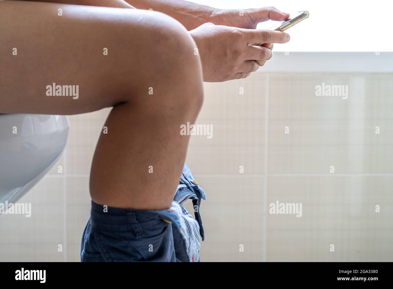 Man sitting on toilet using hi-res stock photography and images - Alamy