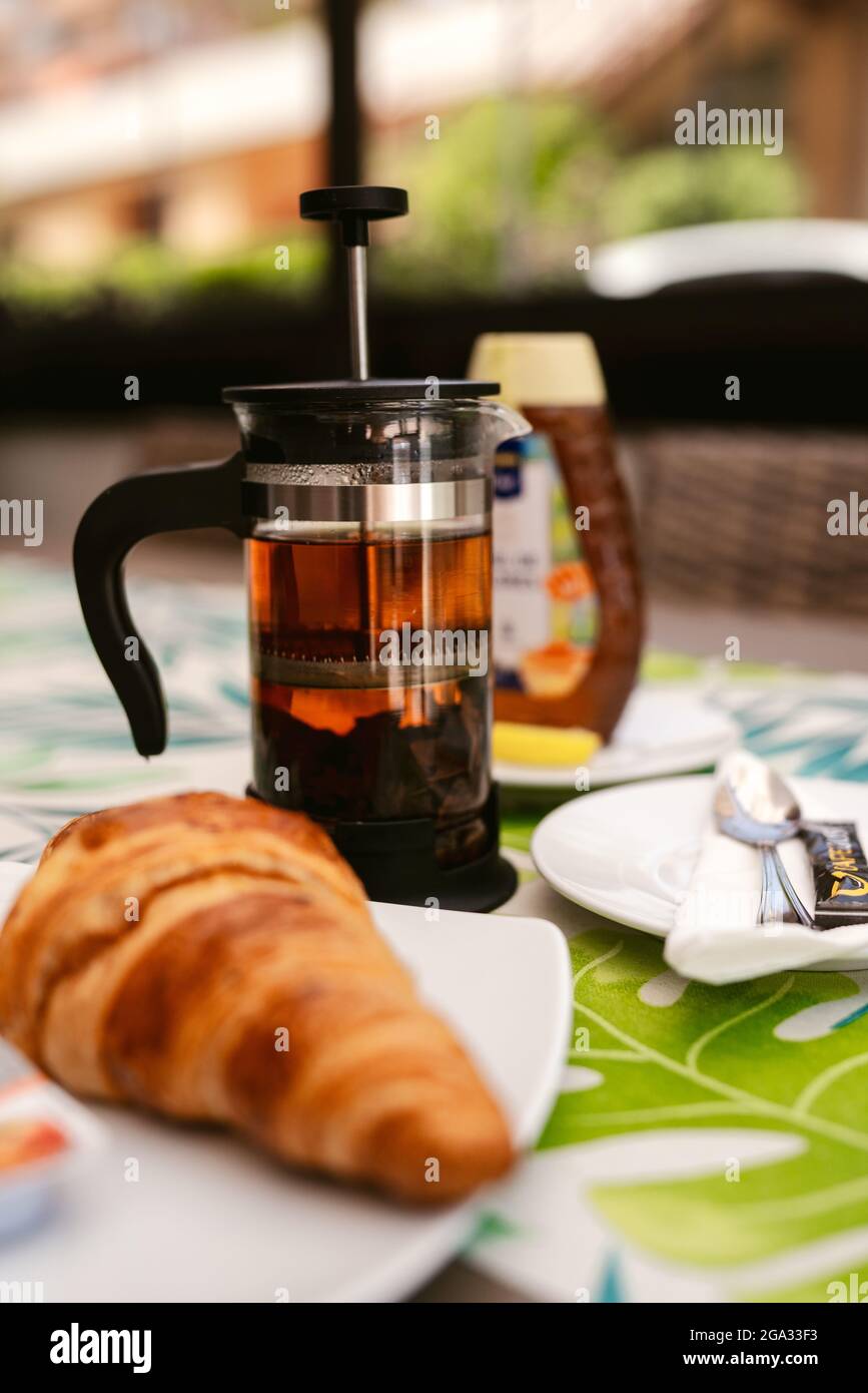 French press and a fresh croissant on the table in an outdoor cafe ...