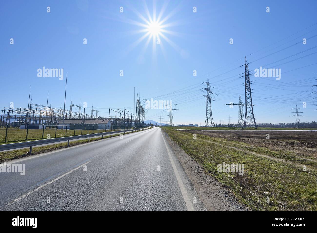 Road with electricity pylons and electricity substation in countryside ...