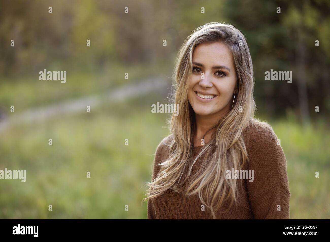 Portrait of a beautiful young woman in a city park; Edmonton, Alberta ...