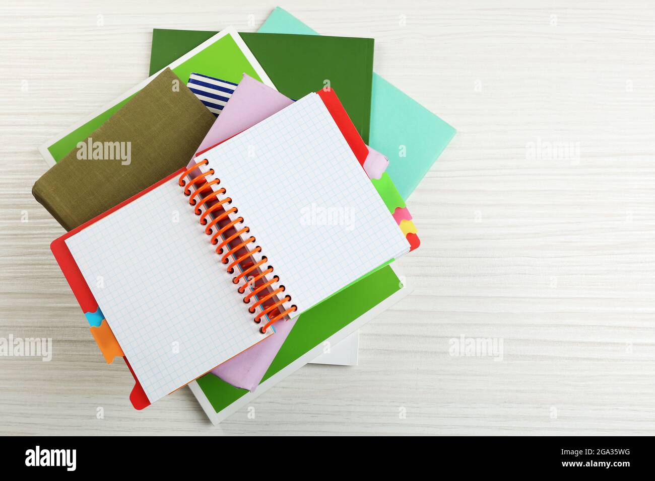 Notebook on top of pile of books and magazines on wooden background ...