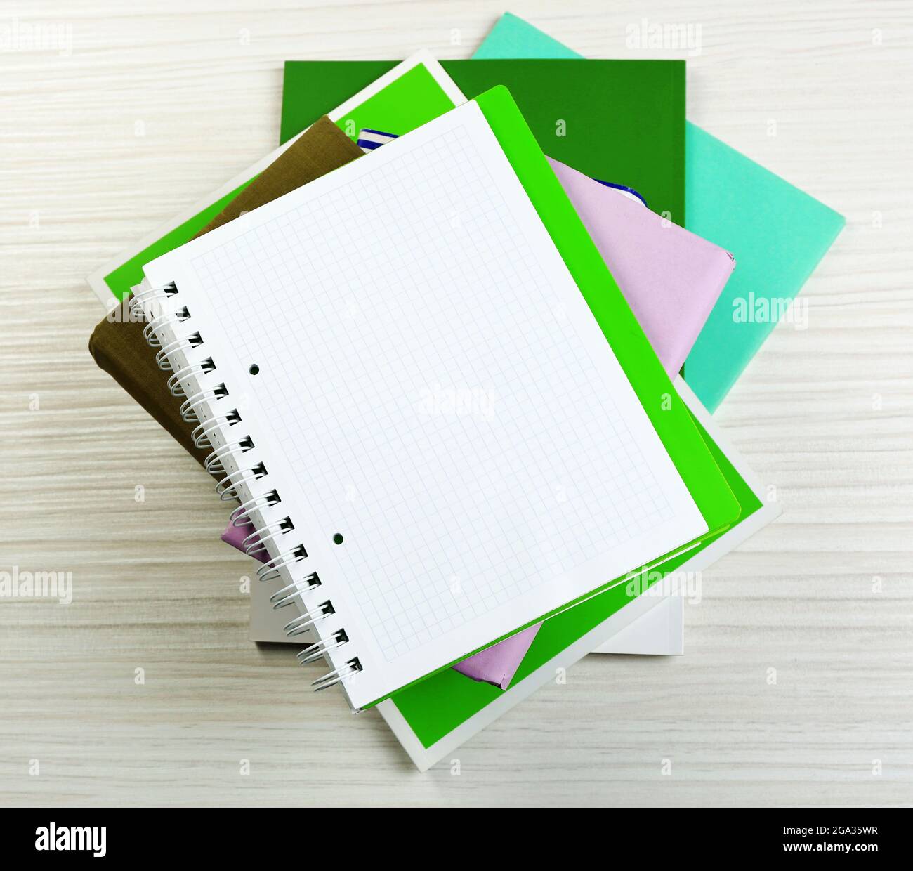 Notebook on top of pile of books and magazines on wooden background ...