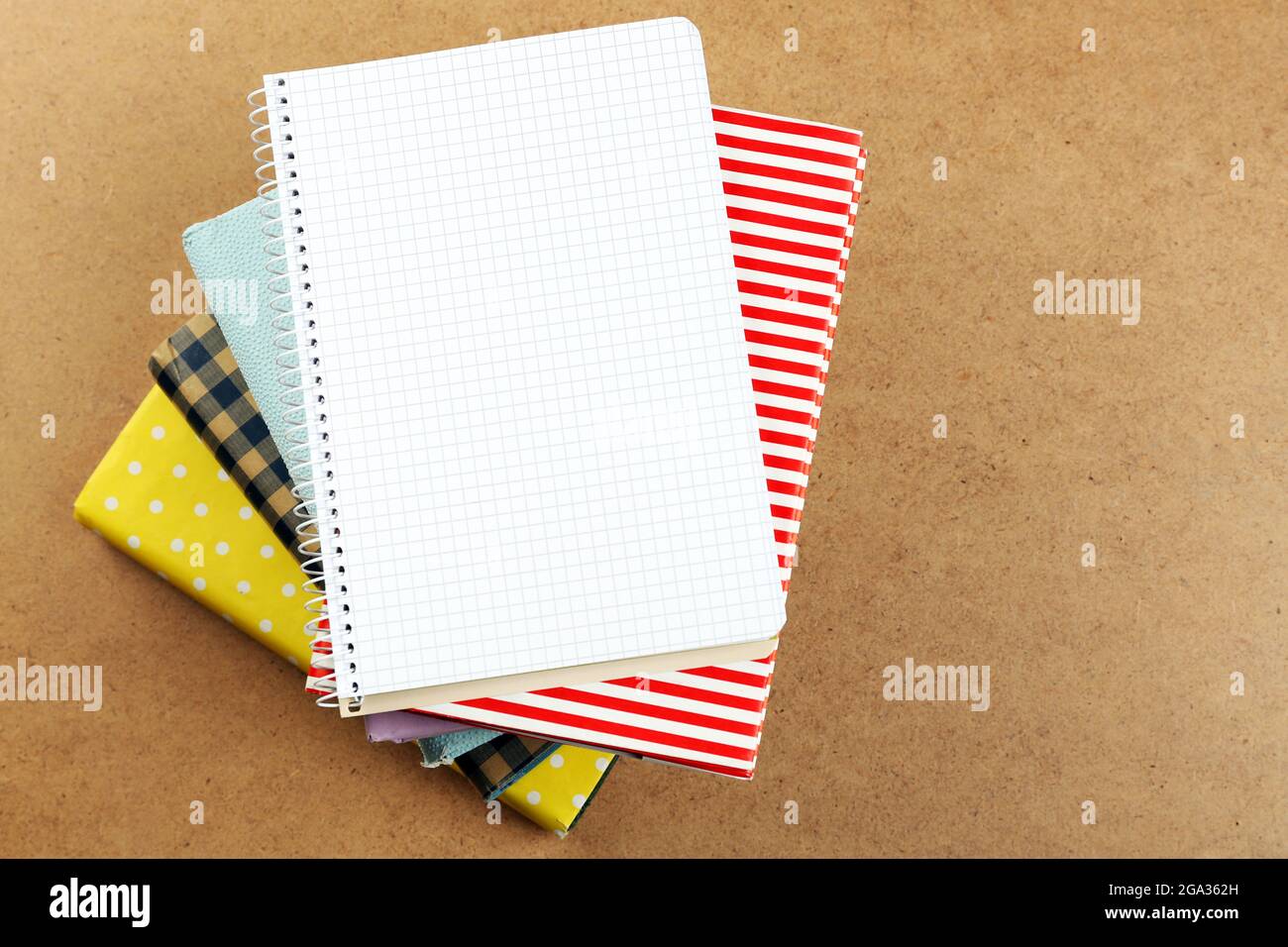 Notebook on top of pile of books and magazines on wooden background ...