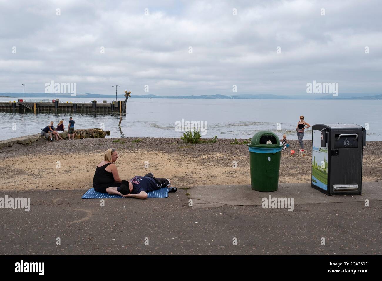Holiday makers in the town of Largs, Scotland relax on the sea front ...