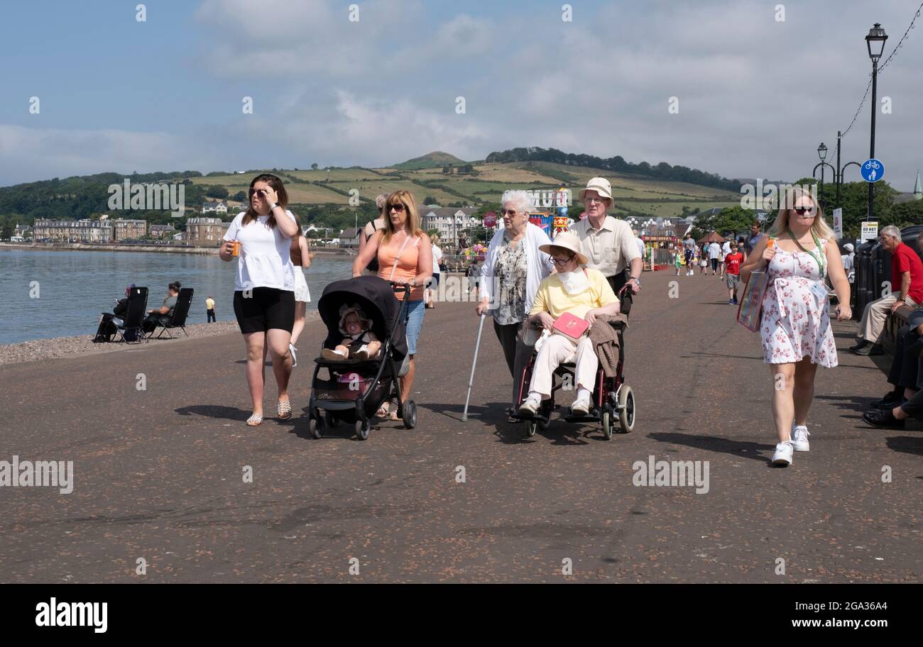 Holiday makers strolling along the promenade in the seaside town of ...