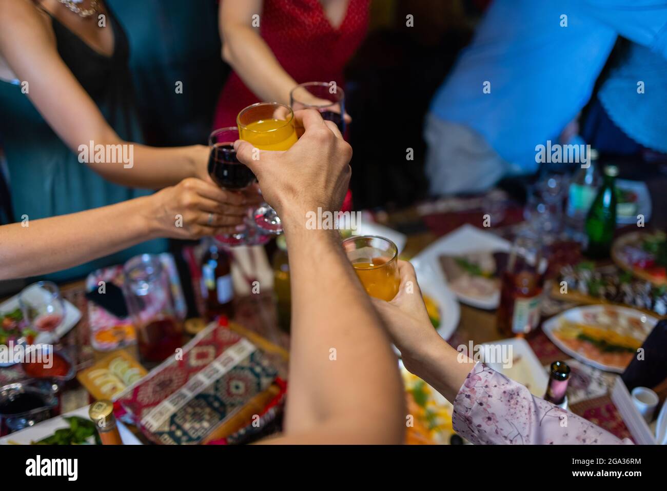 Clinking glasses with alcohol and toasting, party Stock Photo - Alamy