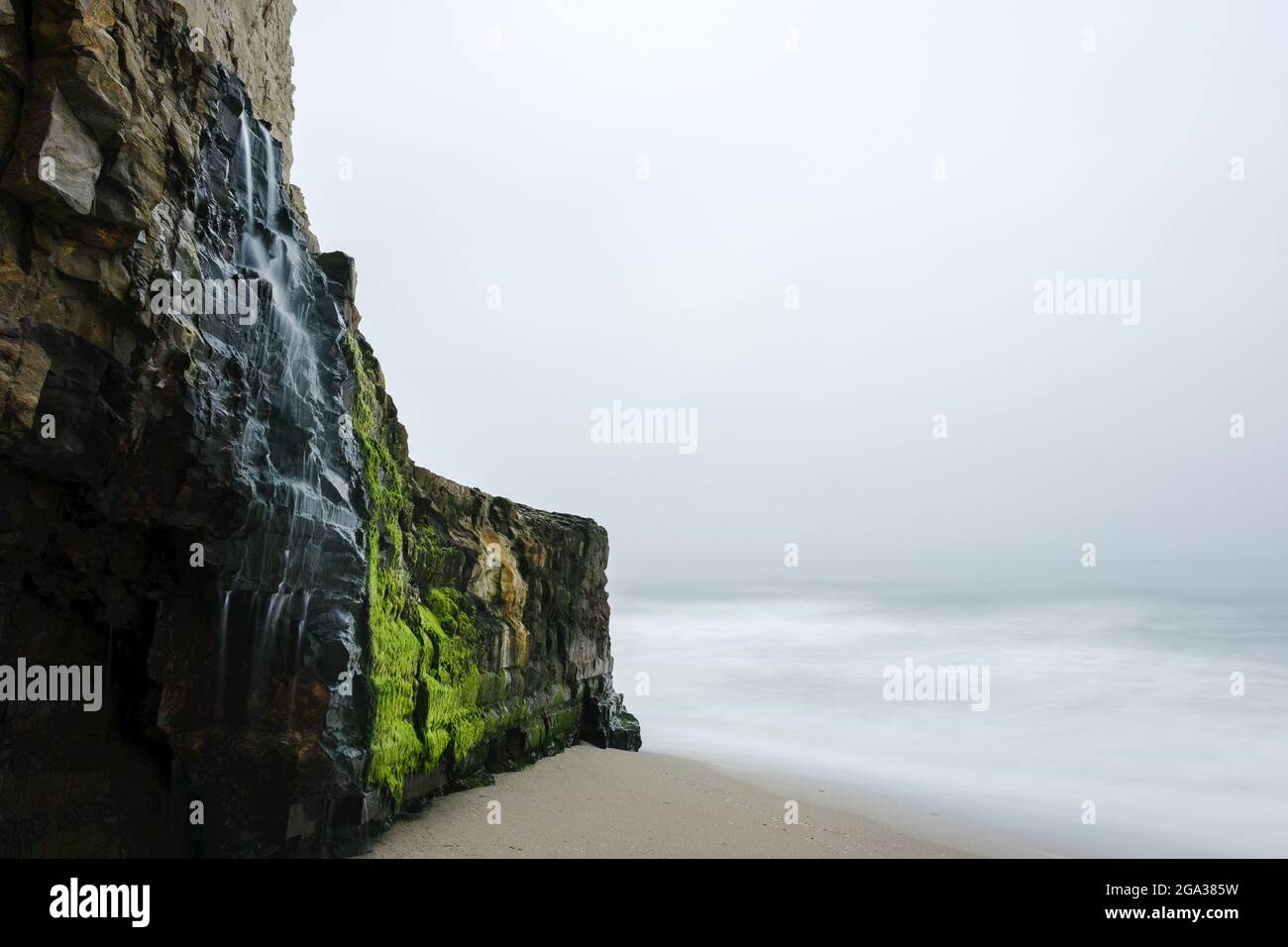 Waterfall over the rugged cliff along the beach and coast at Wilder ...