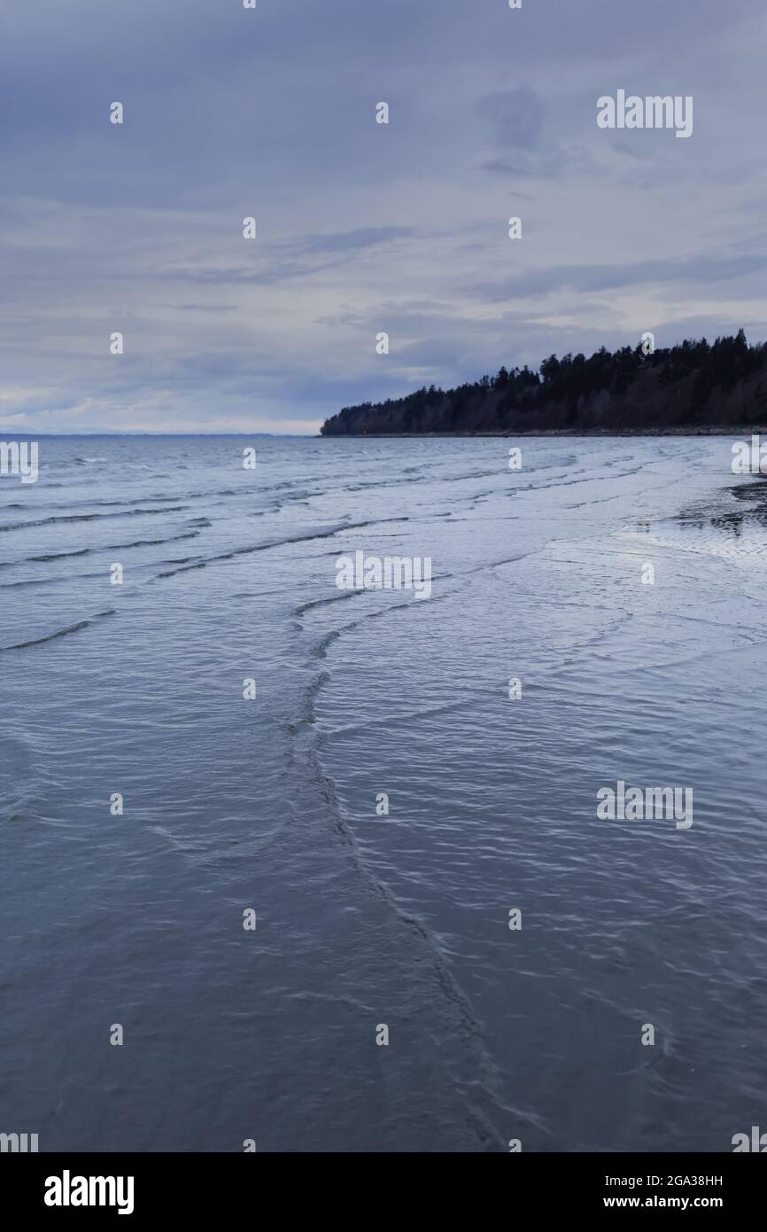 Low tide of the Pacific Ocean rushing in along the Pacific coast at ...