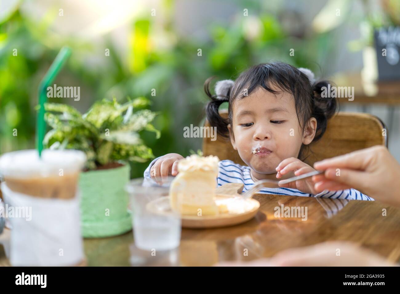 Sweet Southeast Asian female child eating a slice of cake Stock Photo ...