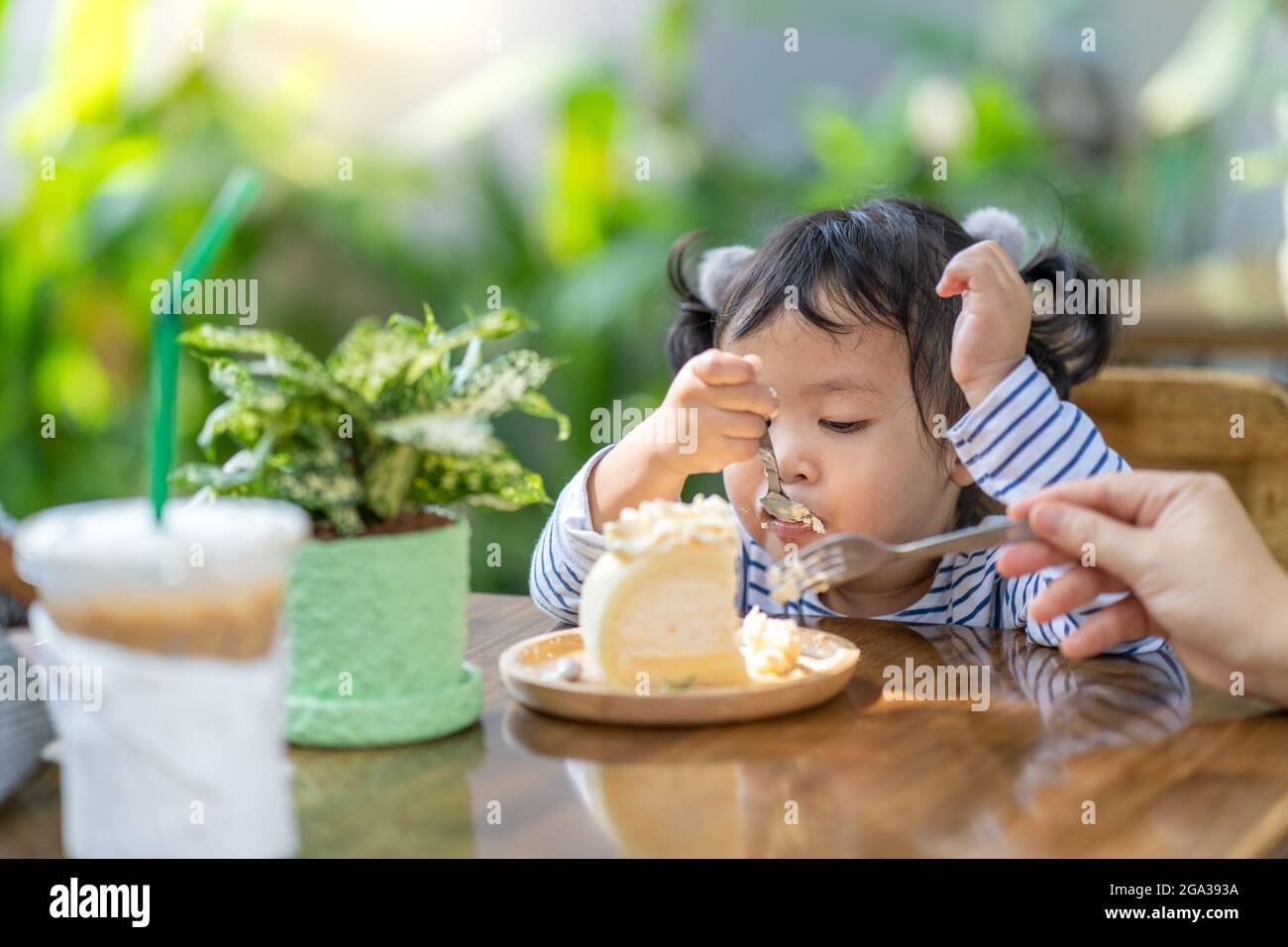 Sweet Southeast Asian female child eating a slice of cake Stock Photo ...