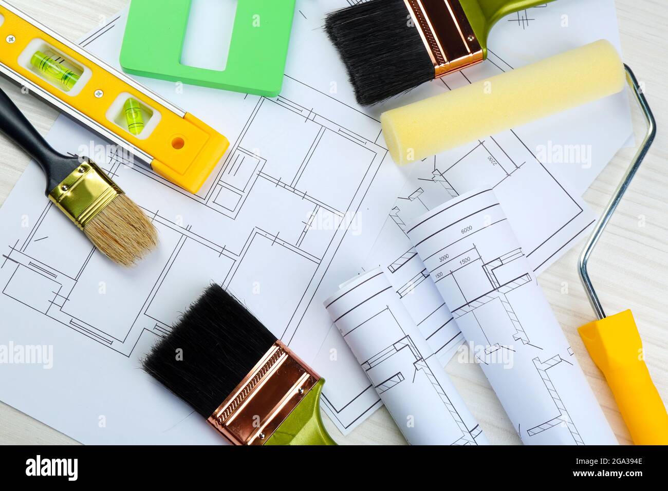 Construction instruments, plan and brushes over house plan on wooden ...